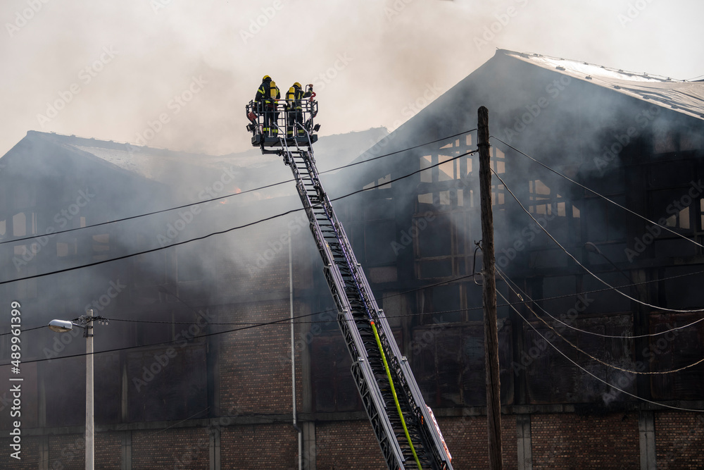 Dramatic scene of Firefighters rising on a mechanical sliding ladder ...