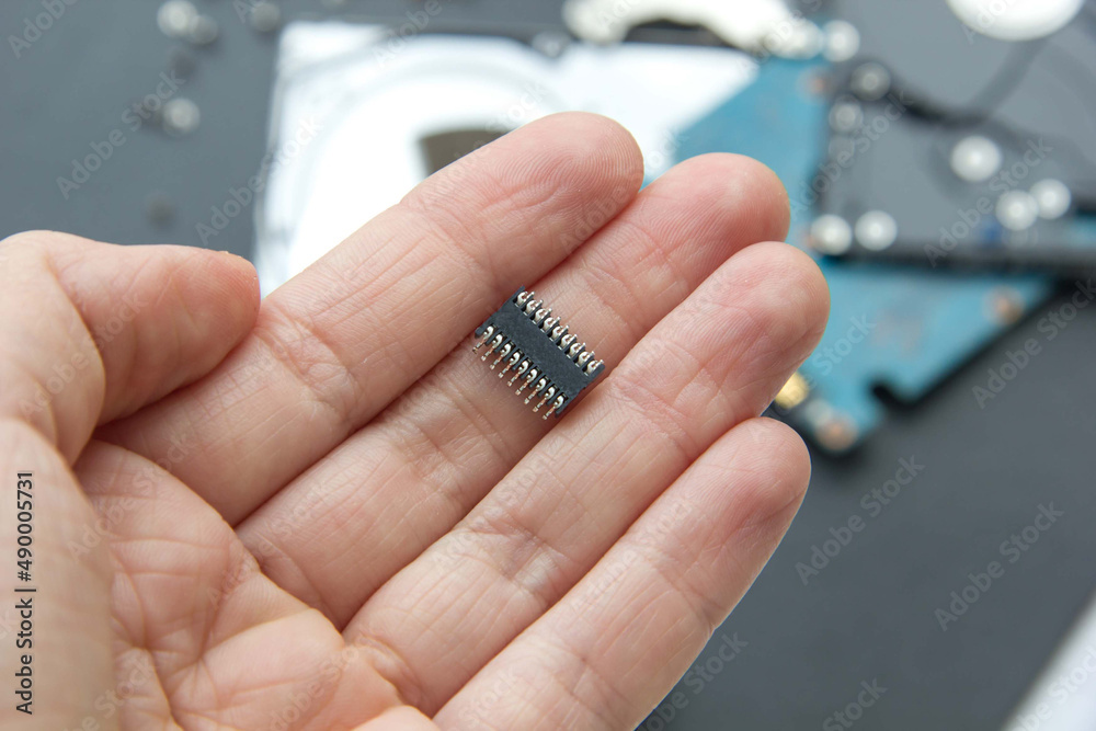 Hand holds chip compenent. Embedding the chip under human skin ...