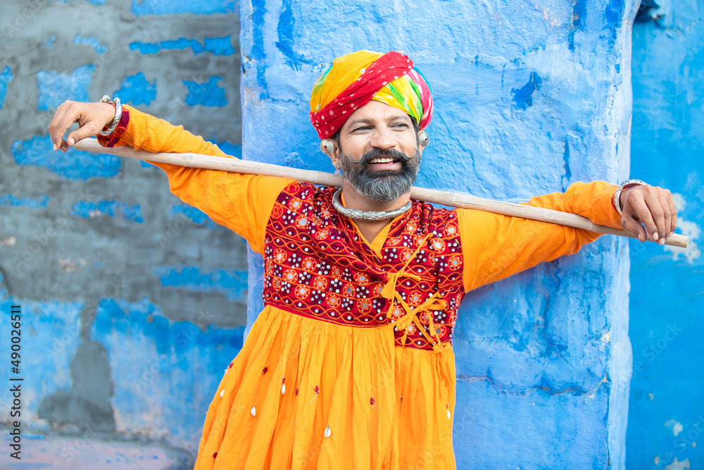 Happy traditional north indian man wearing colorful attire holding wood ...