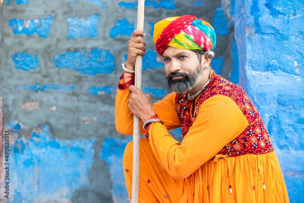 Happy traditional north indian man wearing colorful attire holding wood ...