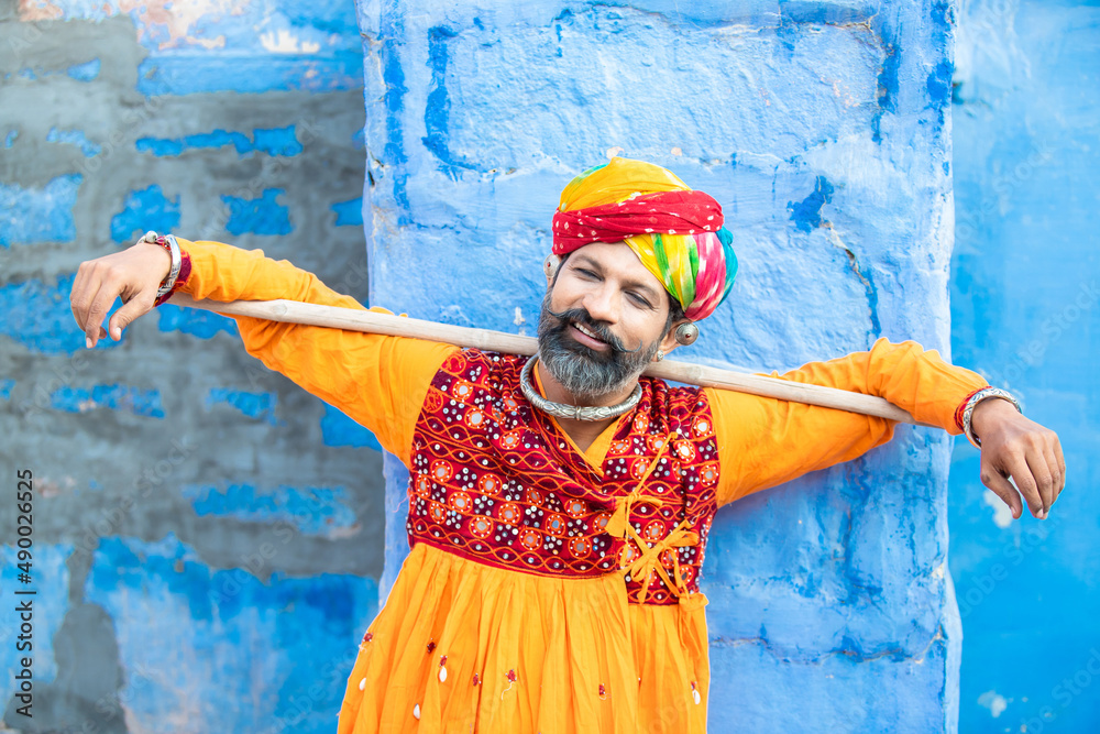 Happy traditional north indian man wearing colorful attire holding wood ...