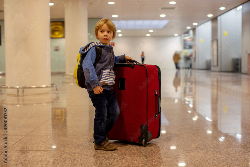 Cute baby boy waiting boarding to flight in airport transit hall near ...