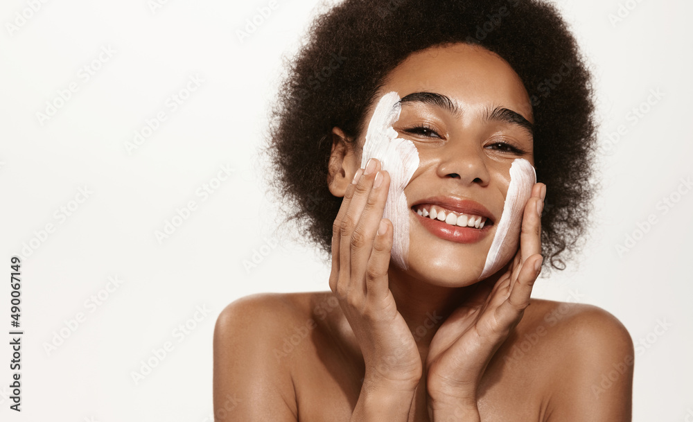 Cheerful female model applies foaming cleanser, has clean fresh healthy ...