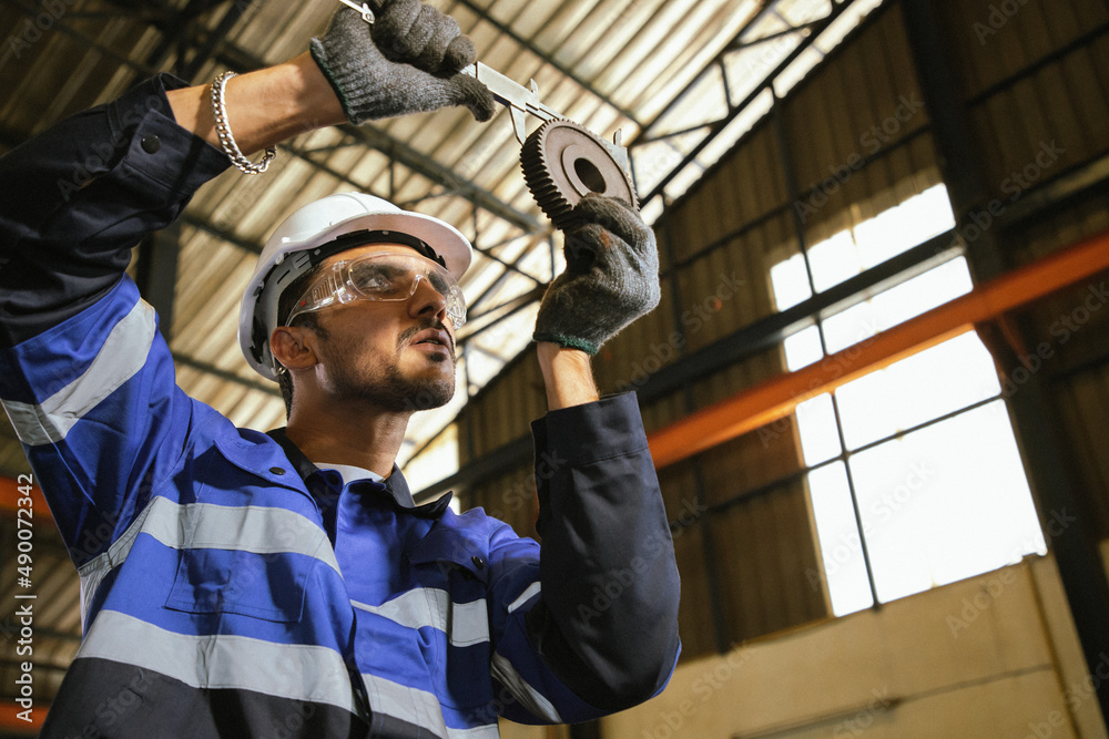 Handsome engineer worker wearing safety goggles measure the size of the ...