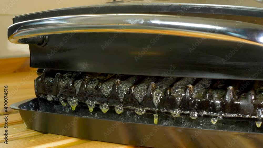 Closeup of hot fat draining into the drip tray from (unseen) food ...