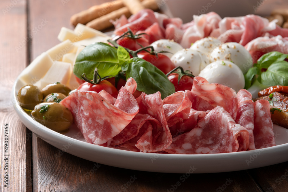Piatto di tipici cibi italiani, salame, mozzarella, pecorino ...