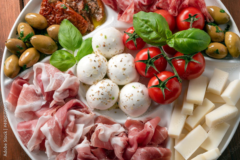 Piatto di tipici cibi italiani, salame, mozzarella, pecorino ...