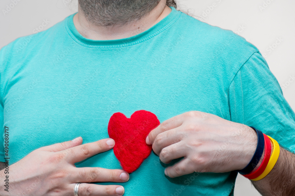 An adult, unshaven man holds a red heart in his hand. A symbol of ...