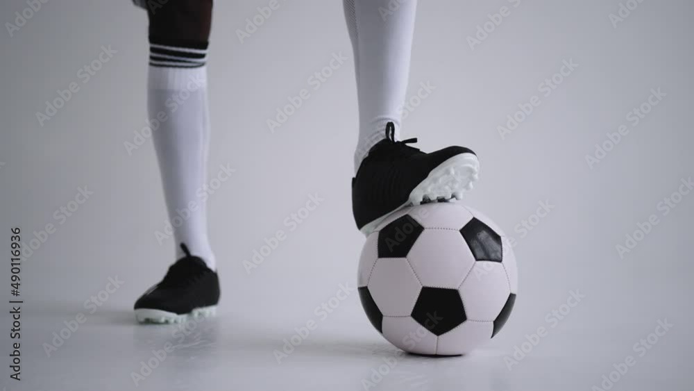 football ball and legs of football in boots and knee socks in studio ...