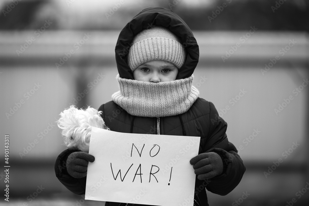 Little refugee girl with a sad look and a poster that says no to war ...