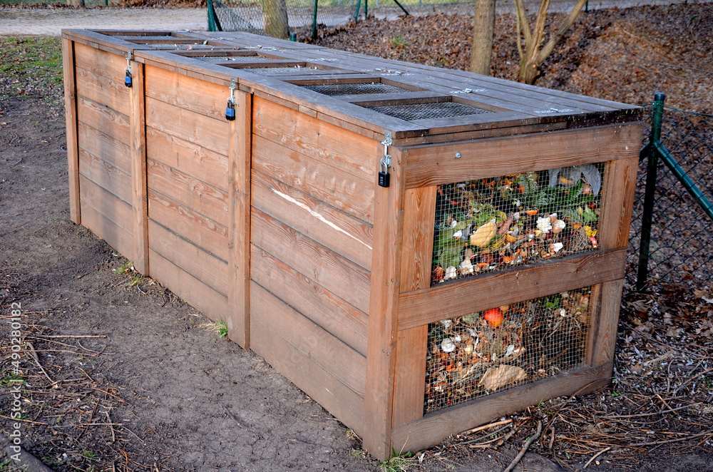 Wood composter with mesh on the sides. Inside are leftovers from the ...