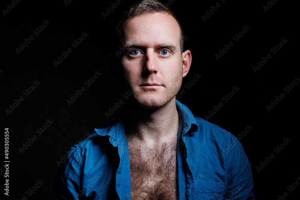 A young handsome man shaves his stubble with a modern electronic razor ...