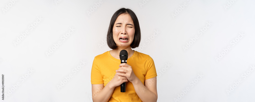 Crying asian girl singing heartbroken in microphone, holding mic and ...