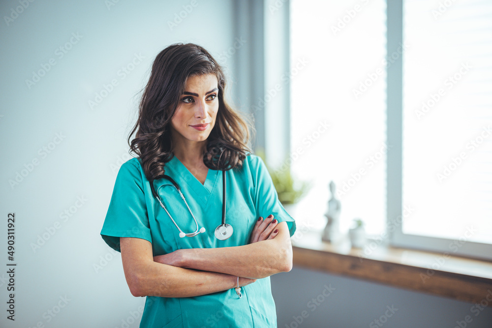 Female nurse wearing green scrubs, arms crossed. Medical professional ...