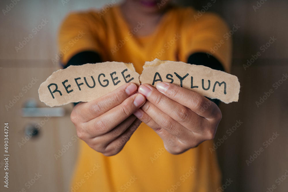 Hand with pieces of paper with words Refugee and Asylum message for ...