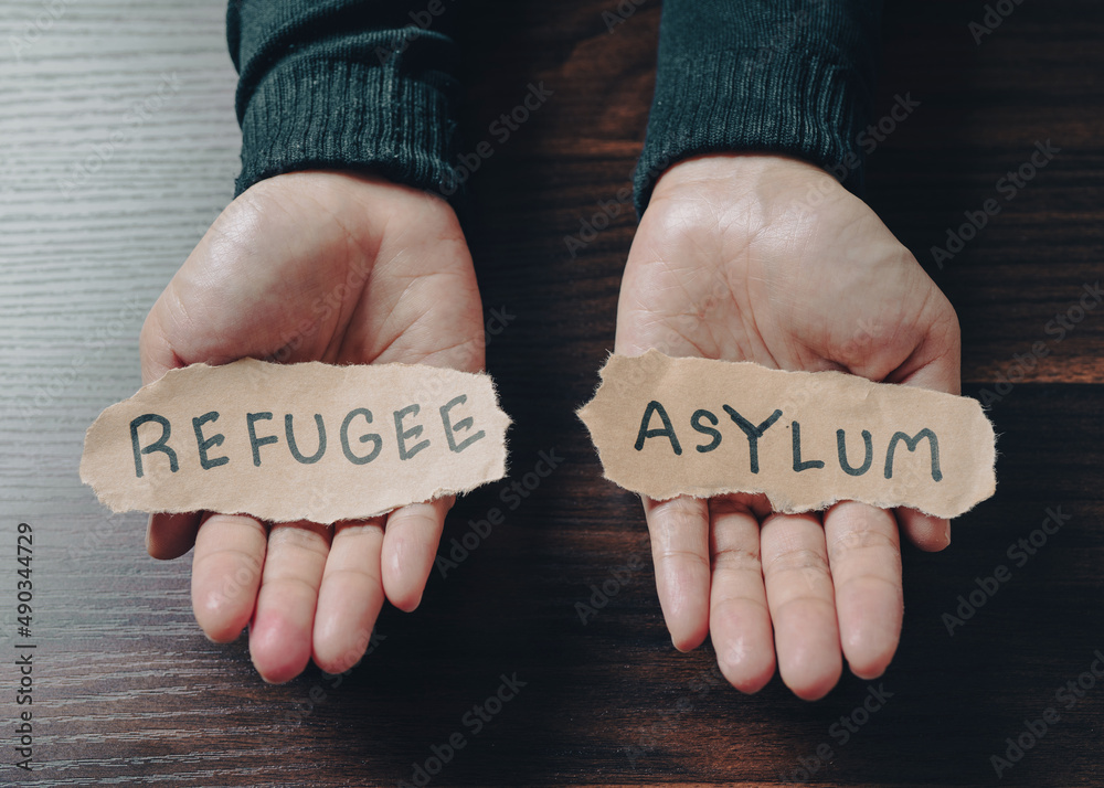 Hand with pieces of paper with words Refugee and Asylum message for ...