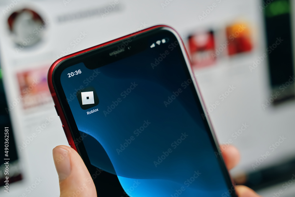 Man holding a smartphone and playing the Roblox mobile game. An ...