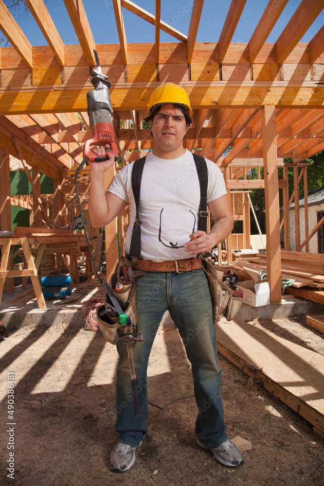 Construction worker wearing a hard hat, tool belt and holding an ...