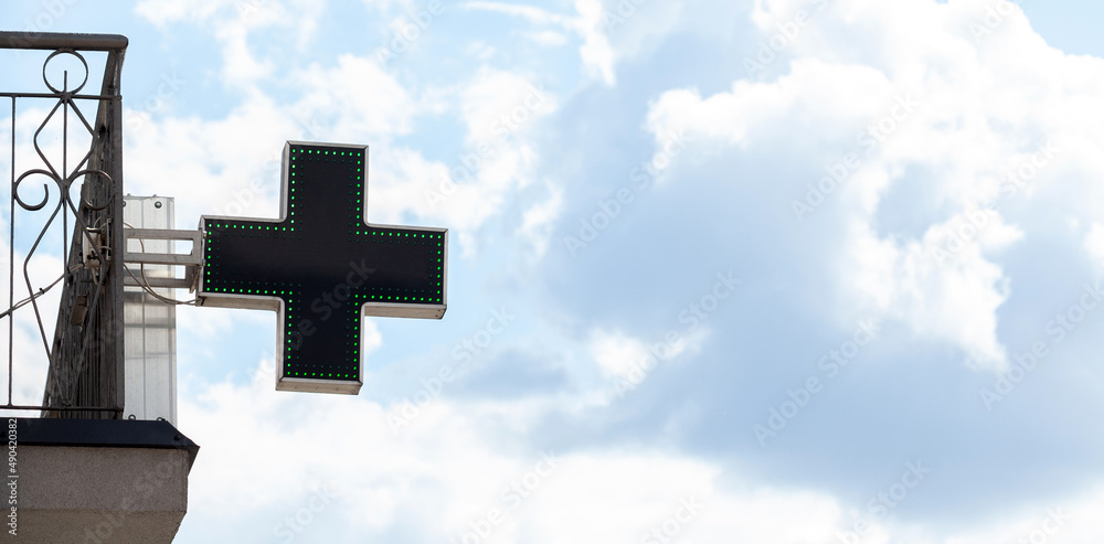 Pharmacy drugstore cross shaped led signage, cloudy sky wide background ...