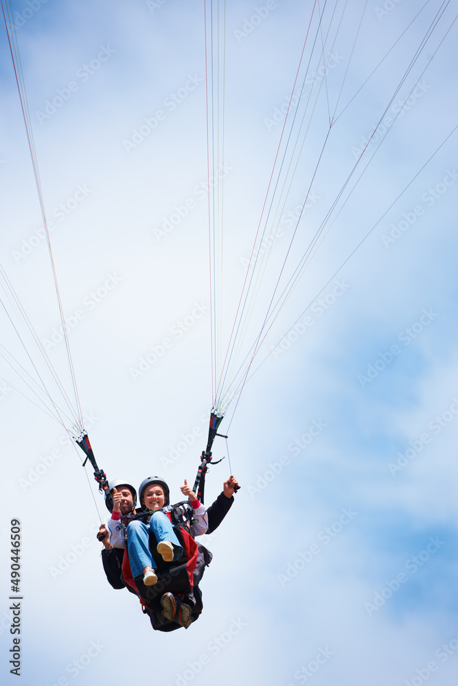 Thumbs up for paragliding. Low angle shot of two people tandem ...
