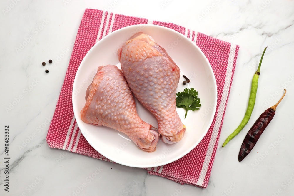 Raw chicken legs or chicken drumsticks with spices on a white plate ...