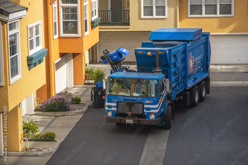 Republic Services trash truck lifts a trash bin full of papers and ...