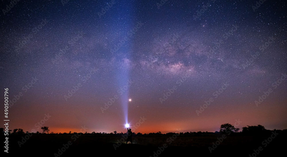 Silhouette tourist with flashlight in open field at night. Space ...