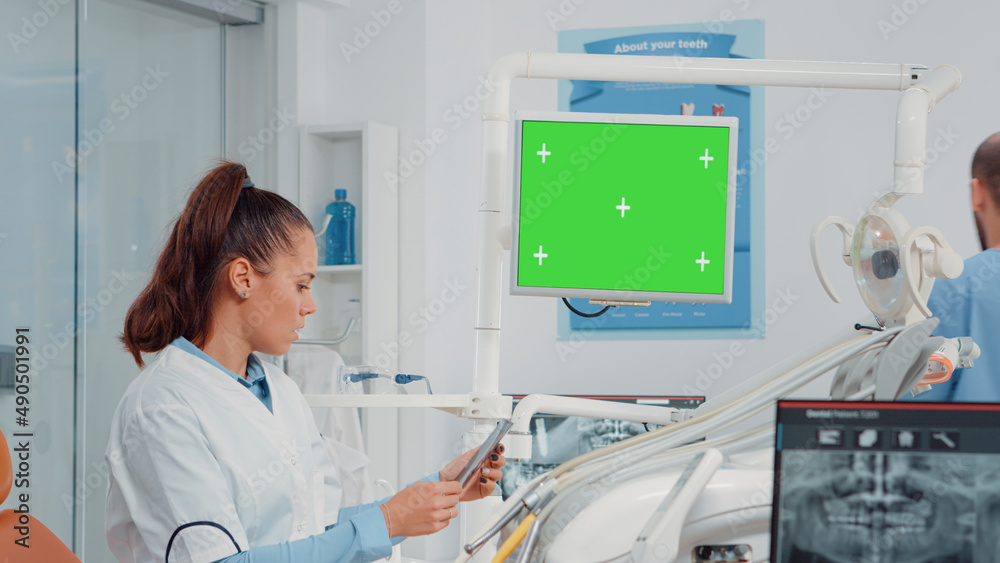 Dentist analyzing horizontal green screen on monitor and radiography of ...