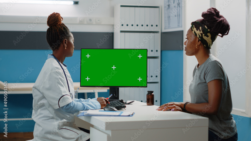 Doctor and patient looking at computer with horizontal green screen in ...