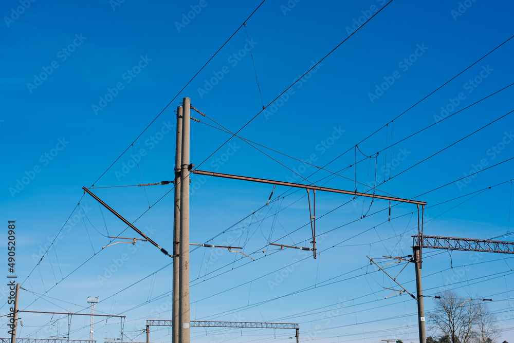 Overhead railway power lines and holding structures under blue sky ...