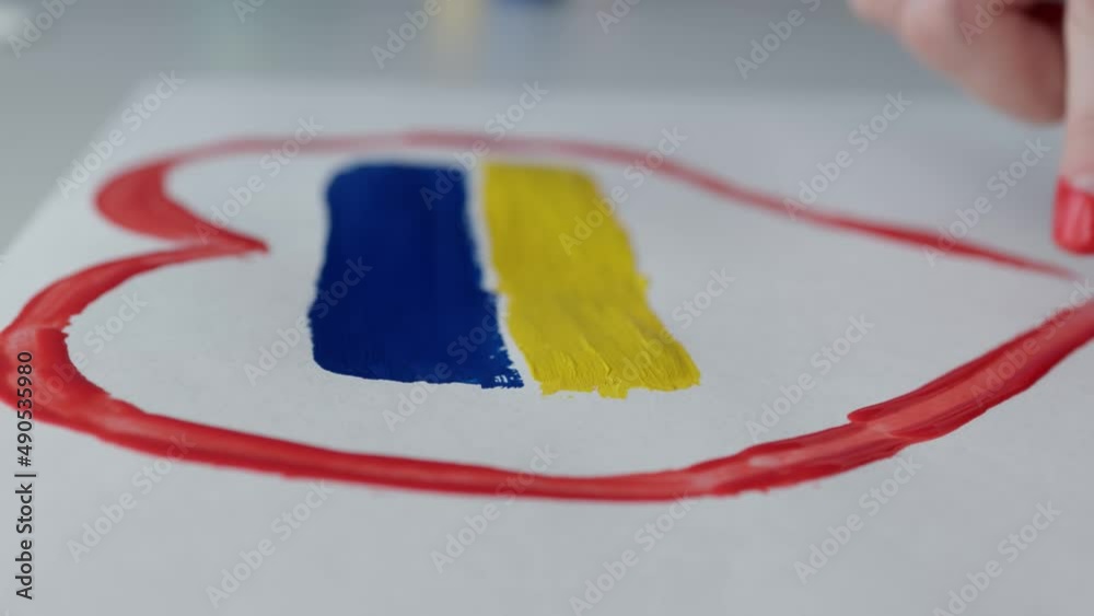 painting yellow blue Ukraine flag with drawing red heart around symbol ...
