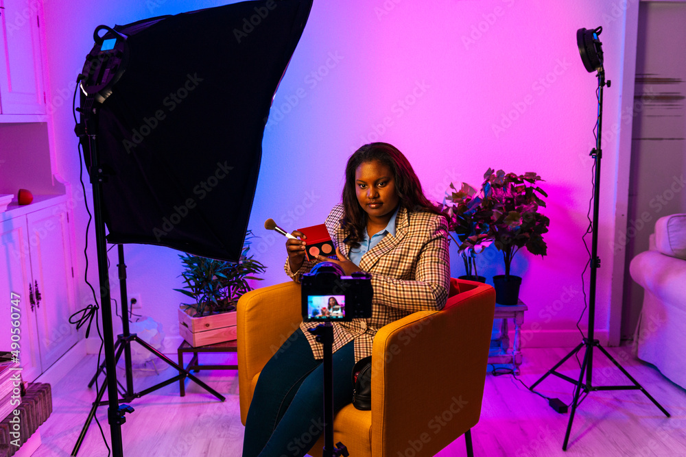 Curvy african american female vlogger in stylish outfit sitting in ...