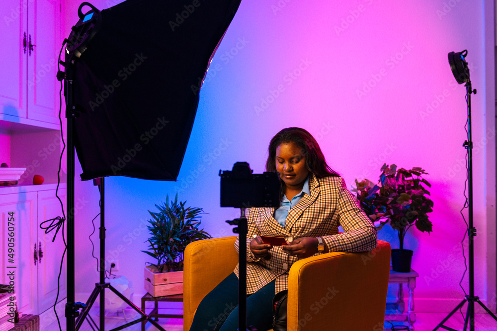 Plus size young black woman vlogging on chair at home studio Stock Photo | Adobe Stock