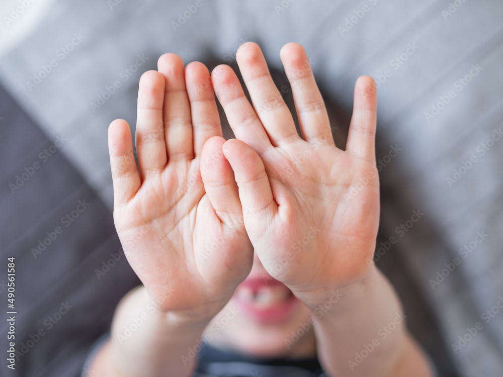 Little boy covers his face with hands. Child refuses to be photographed ...