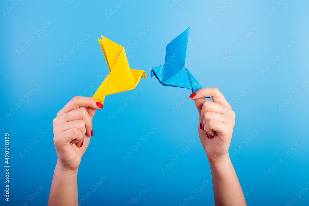 two hands holding doves as a symbol of peace, the flag of Ukraine in ...