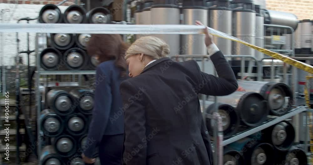 Two female detectives crossing police line at crime scene while a CSI ...