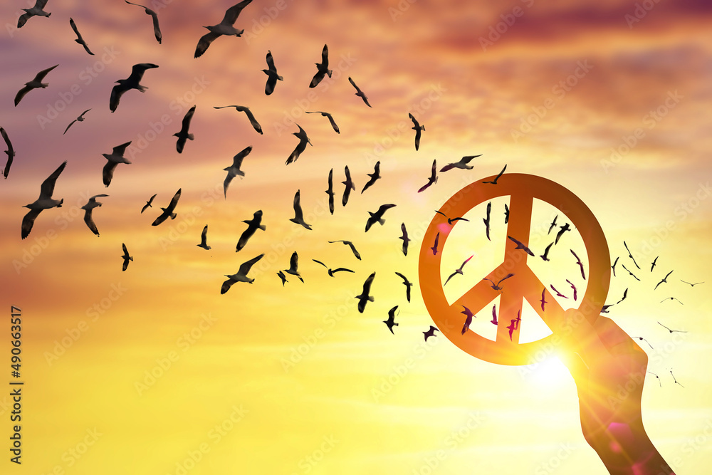 silhouetsilhouette hand holding peace symbol at birds flying ...