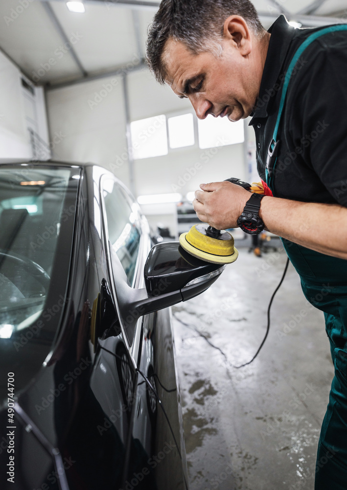 Professional car service worker polishing luxury car with orbital ...