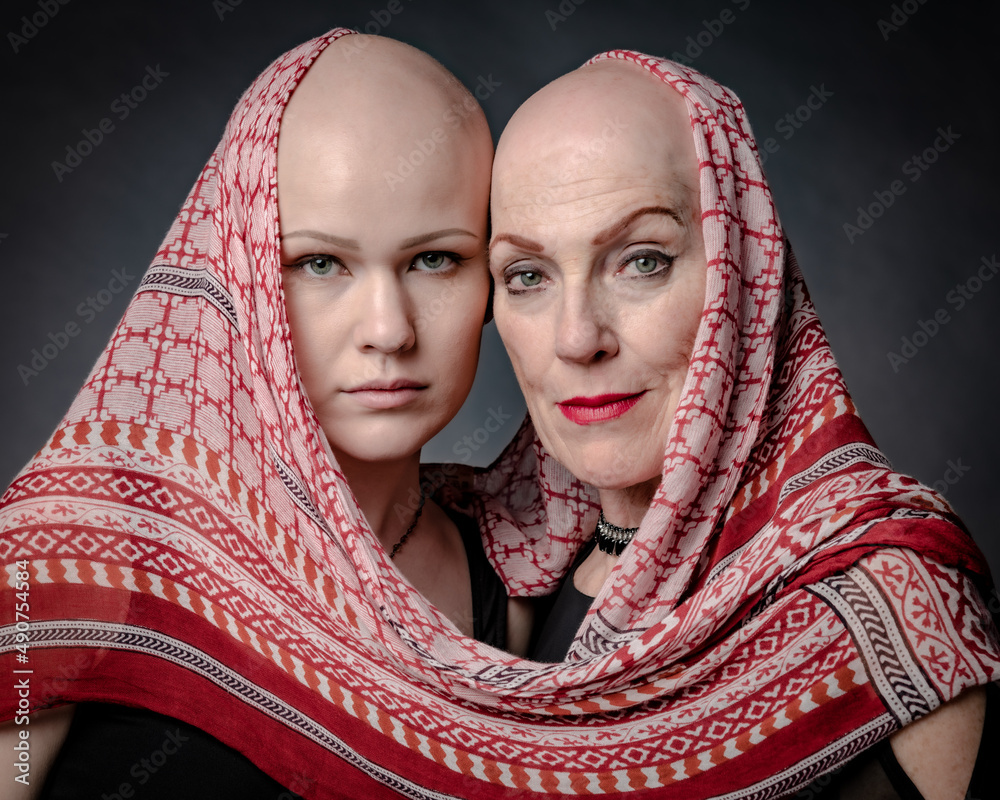 Two beautiful women posing together with a red scarf in a studio ...