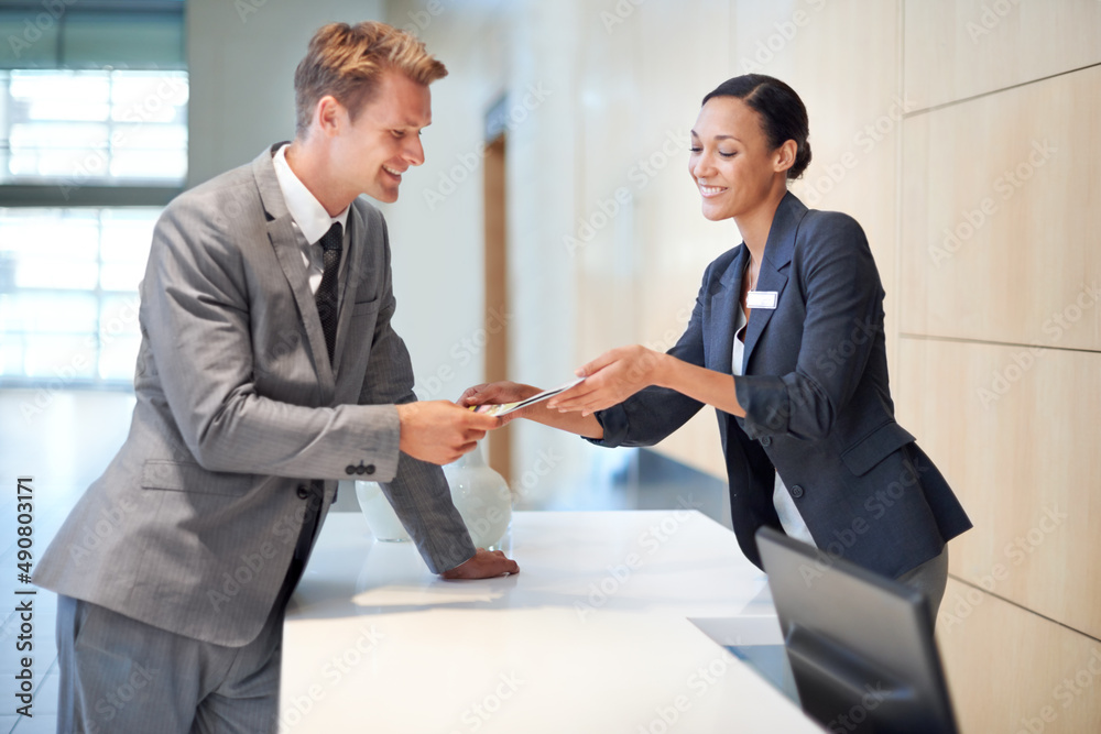 Clocking in for the day. A businessman signing in at a reception desk ...