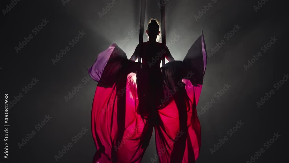 Silhouette of an aerial circus gymnast performing on aerial silk and ...