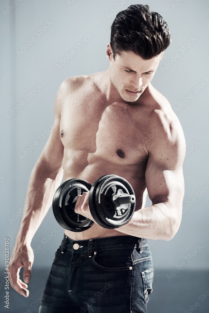 Fully focused on keeping fit. A masculine male with no shirt on lifting ...