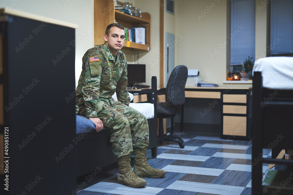 Some call it a dorm, I call it home. Shot of a young soldier sitting on ...