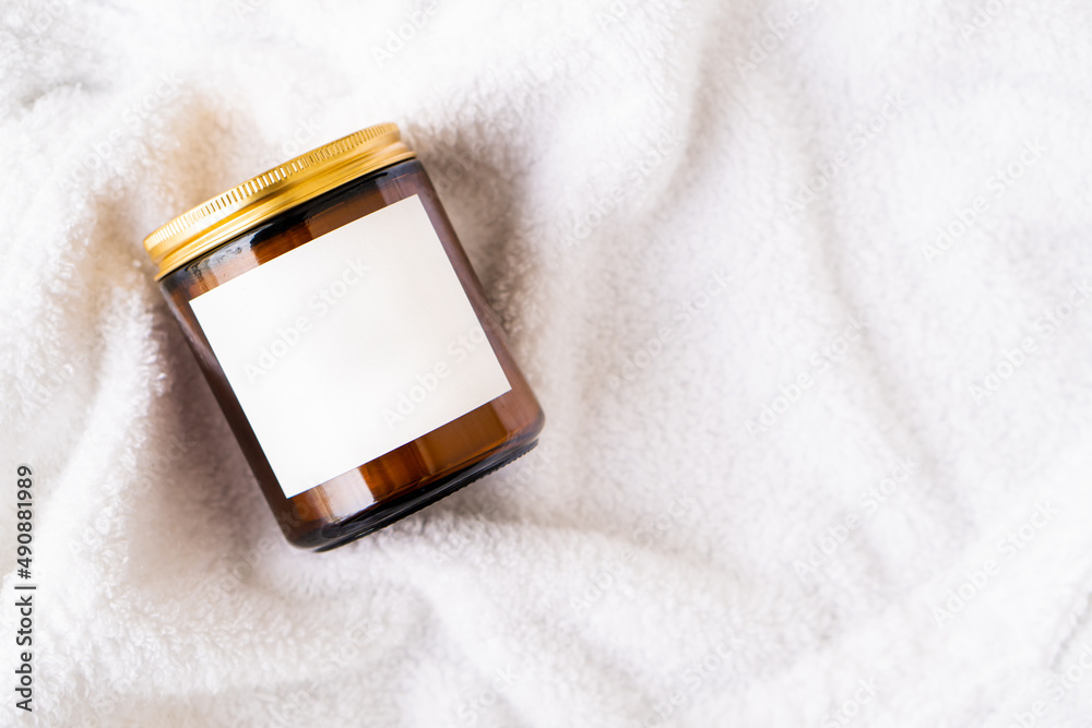Amber glass jar with metal lid and blank label on white cotton fabric ...