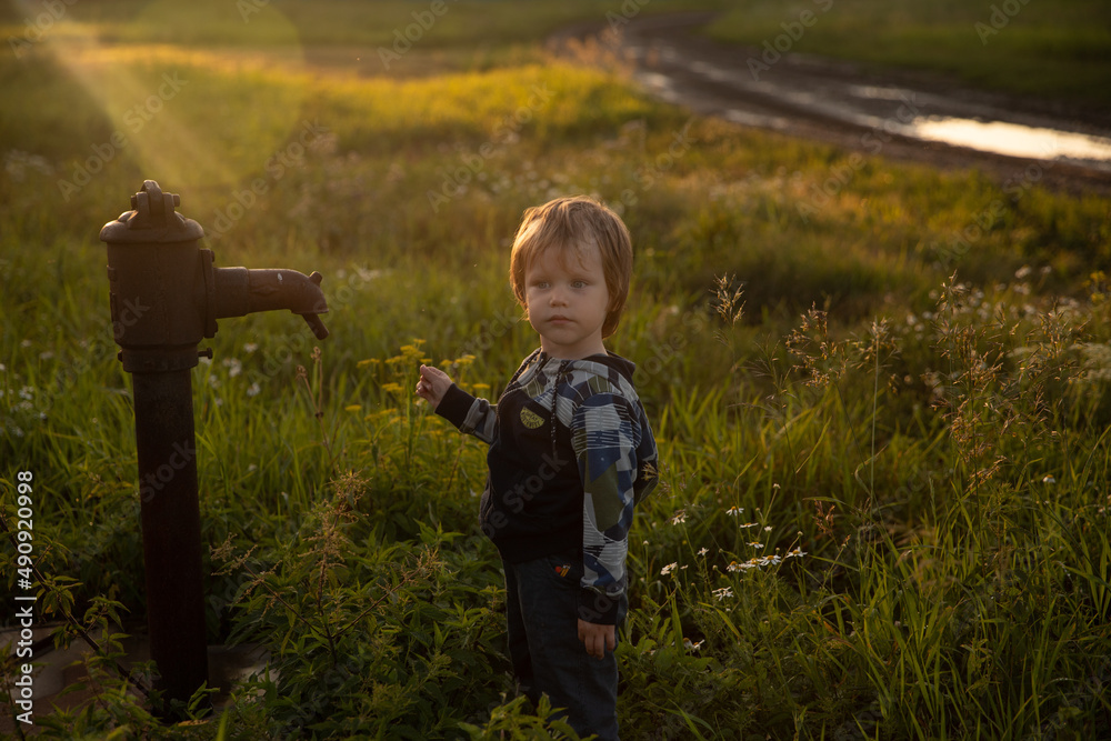A little boy outside in the summer next to a water column Stock Photo ...