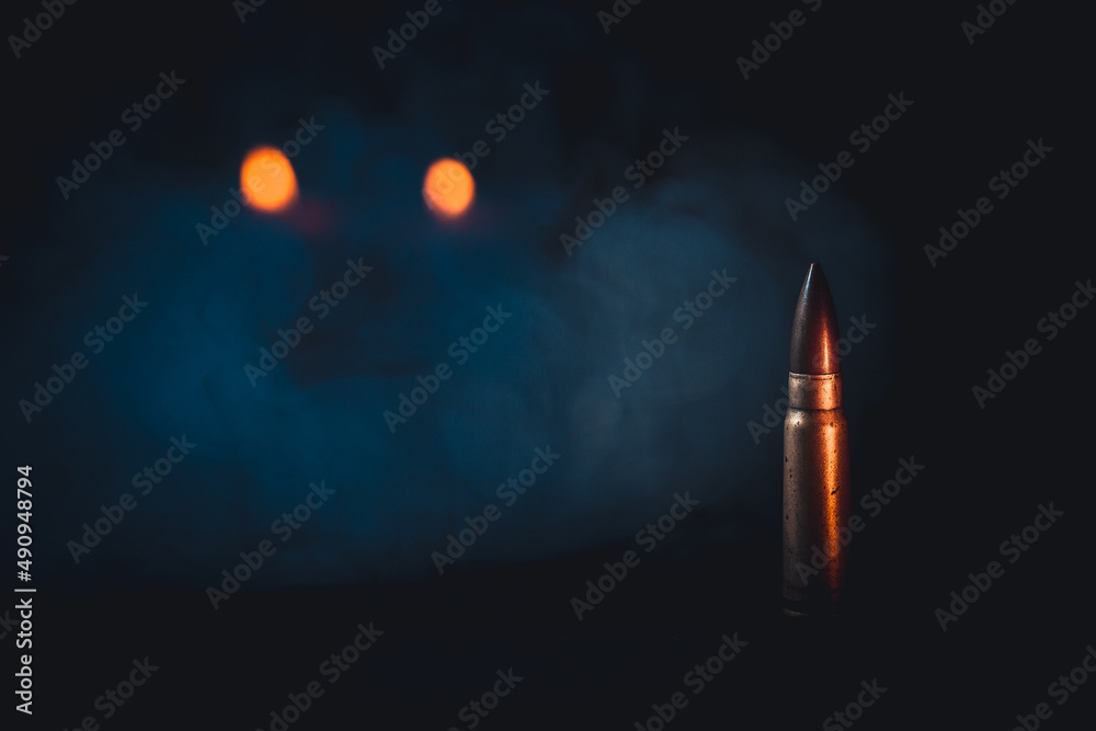 Assault rifle bullet on isolated black background. Candles and smoke in ...