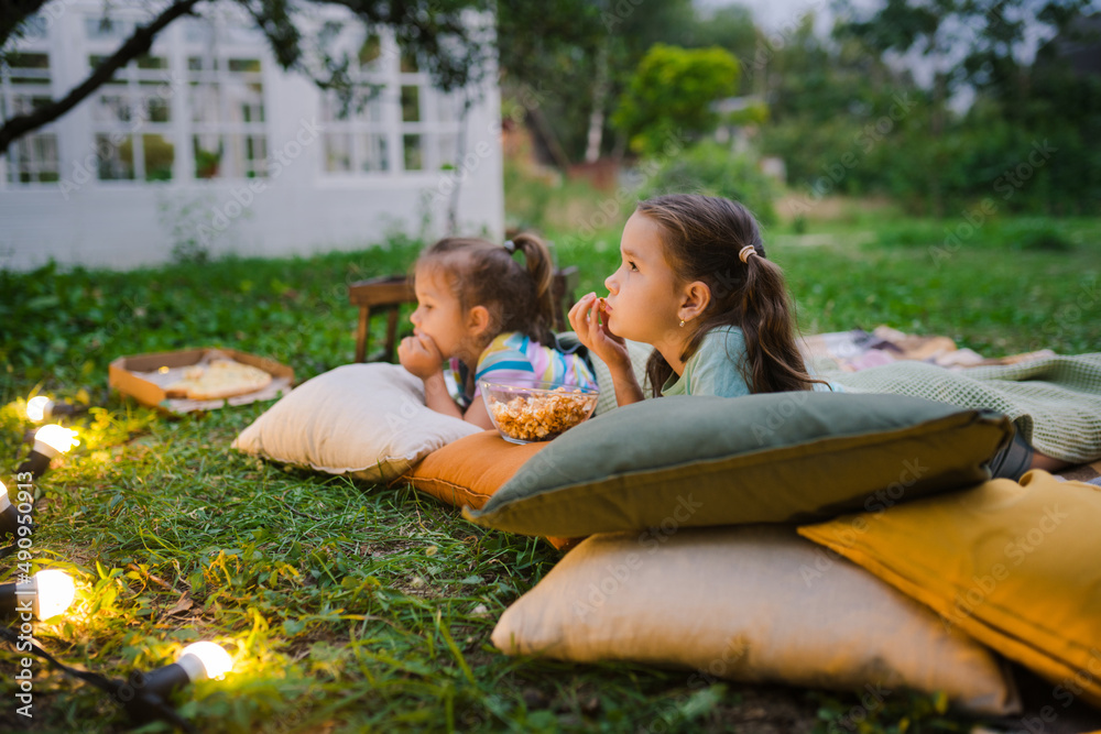 Fototapeta Family summer outdoor movie night. Girls lying on blanket ...