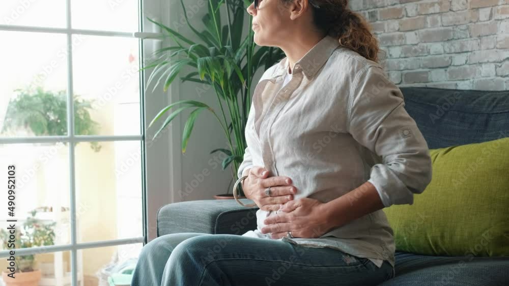 Midsection Of Woman Hands Holding Her Belly Fat Sitting On Sofa At Home