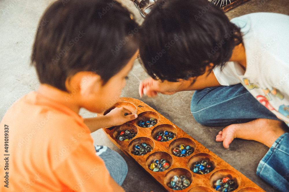 Kids playing traditional game name Congkak. Stock Photo | Adobe Stock
