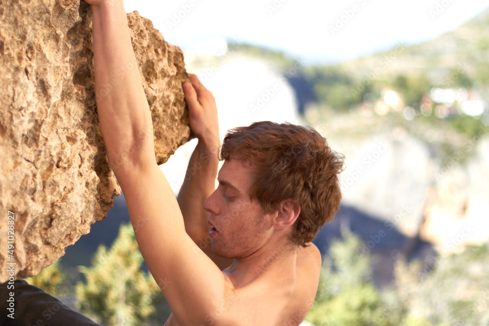 Hes a cliff hanger. Profile of a young rock climber hanging off the ...